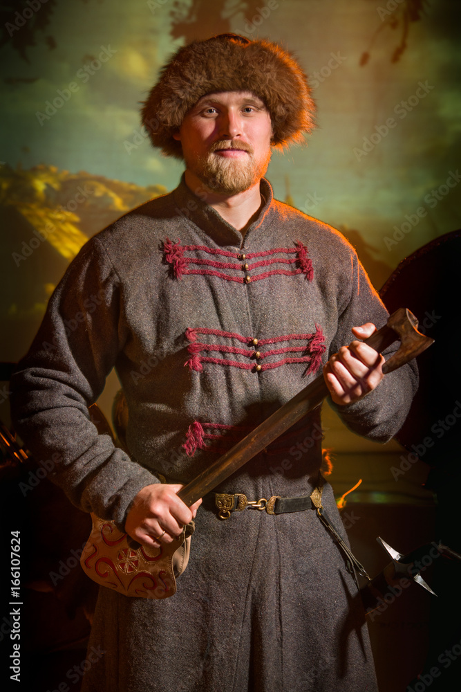 young man with a beard in a medieval Cossack costume with an ax. Stock ...