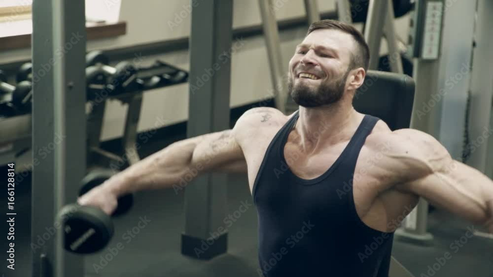 Bodybuilder man trains squat with dumbbells inside gym. Young ...