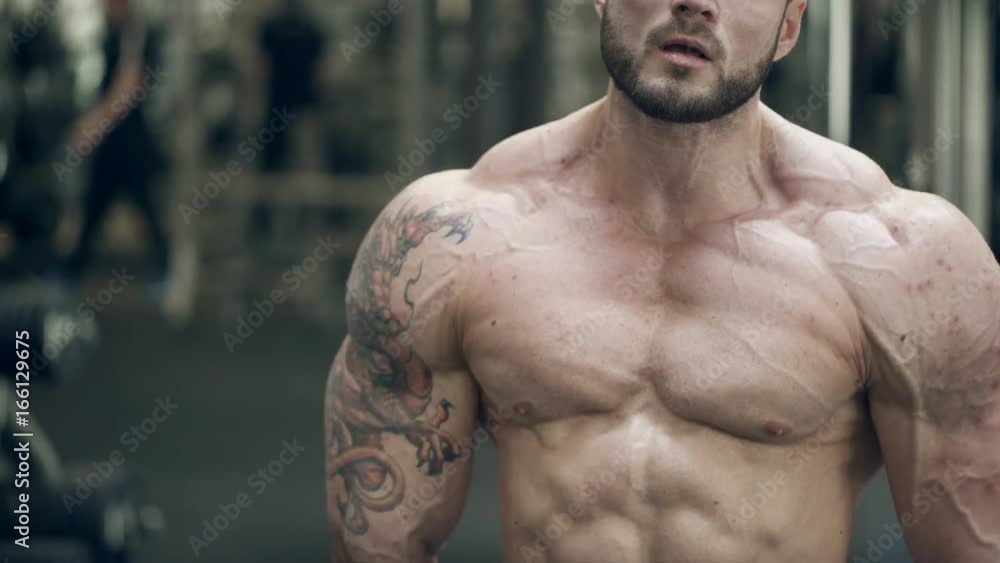 Young bodybuilder posing standing in gym indoor. Hardener man with bare ...