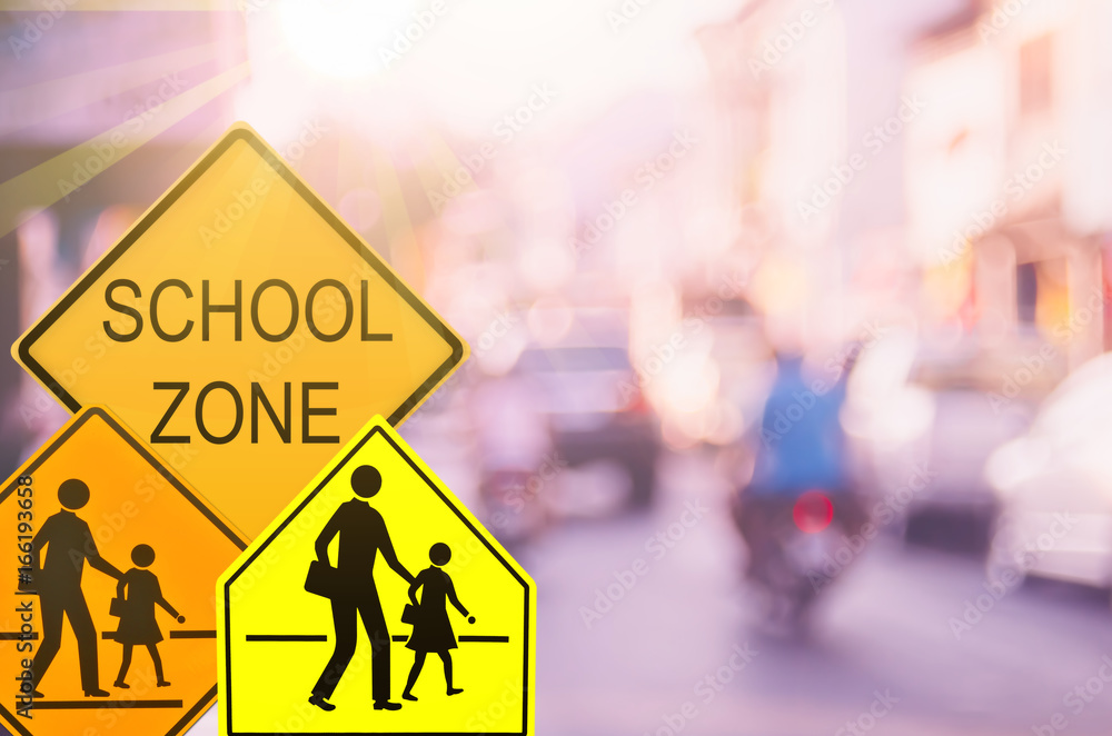 School zone warning sign on blur traffic road with colorful bokeh light abstract background ...