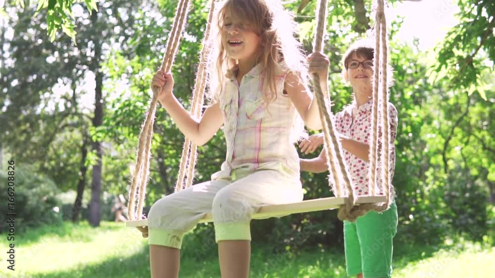 children swinging on a swing in summer Park. two little sisters playing ...