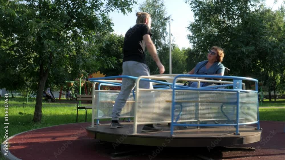 Woman and a man in roundabouts. A mature female in the wheelchair and ...