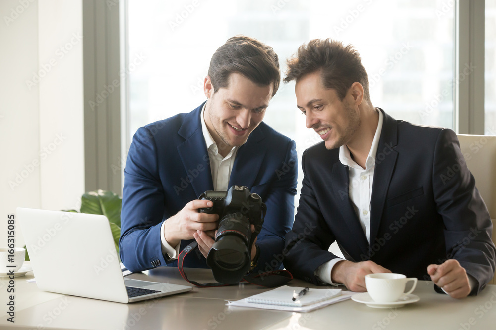 Happy businessman holding new professional camera, showing photographs ...