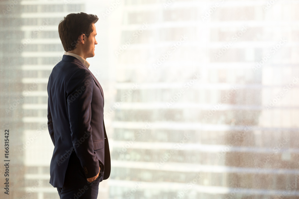 Thoughtful businessman looking at city standing near window, successful ...