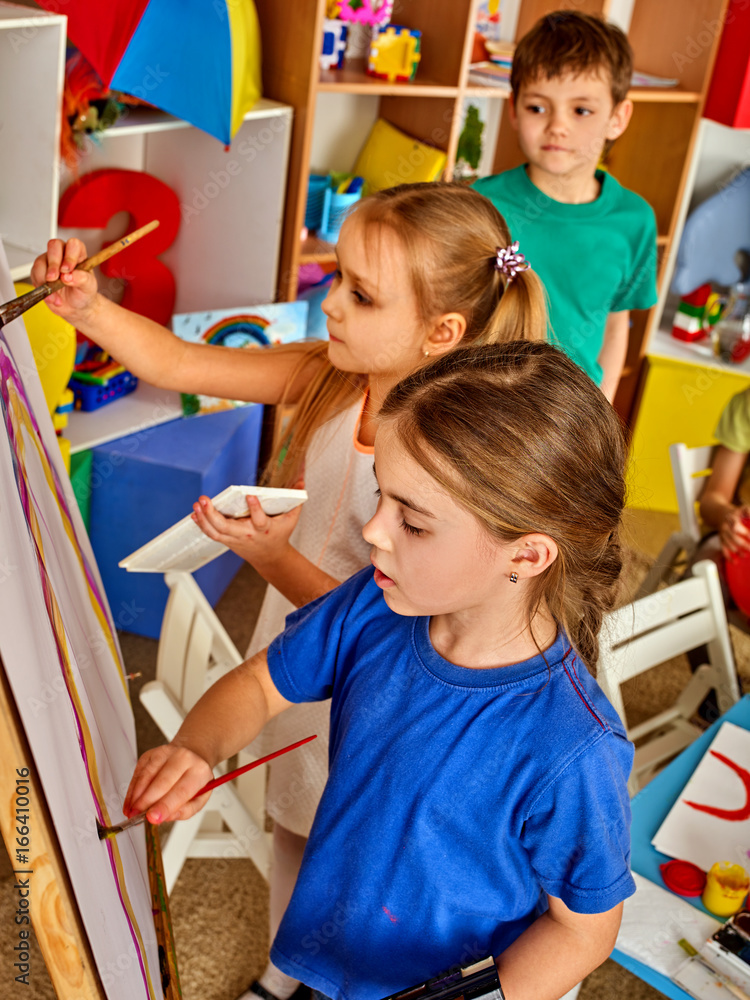 Children painting finger on easel. Group of kids girl and boy with ...