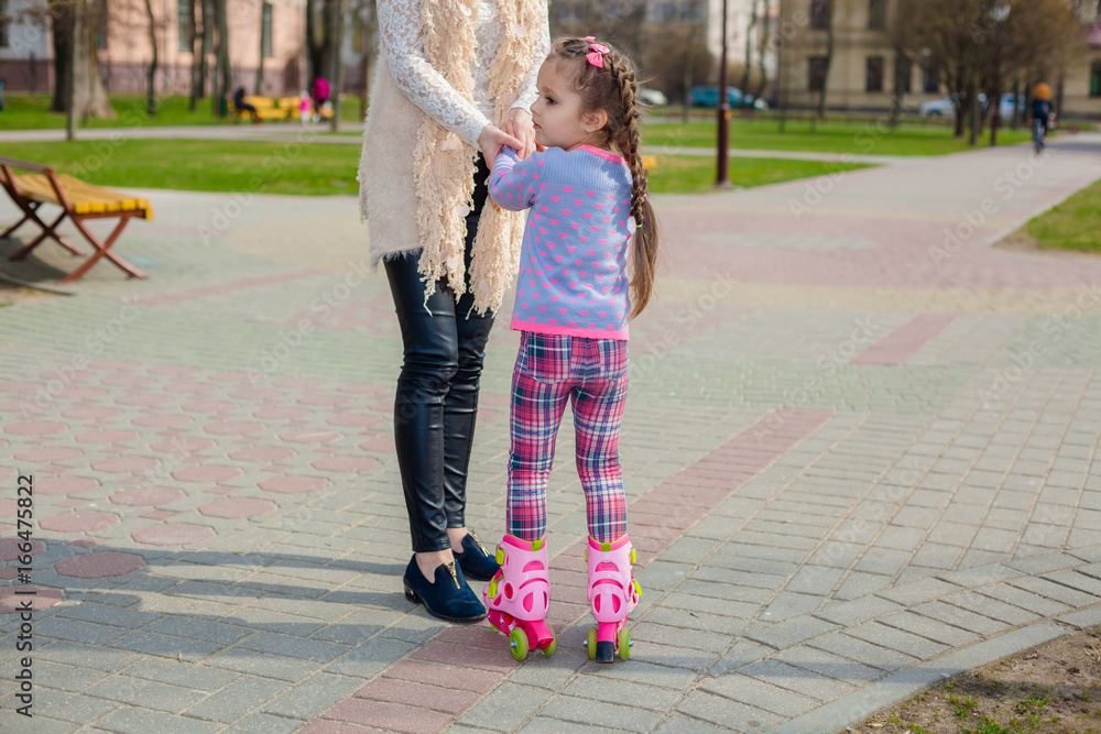 Mom and daughter ride on roller skates. Girl learning to roller skate ...