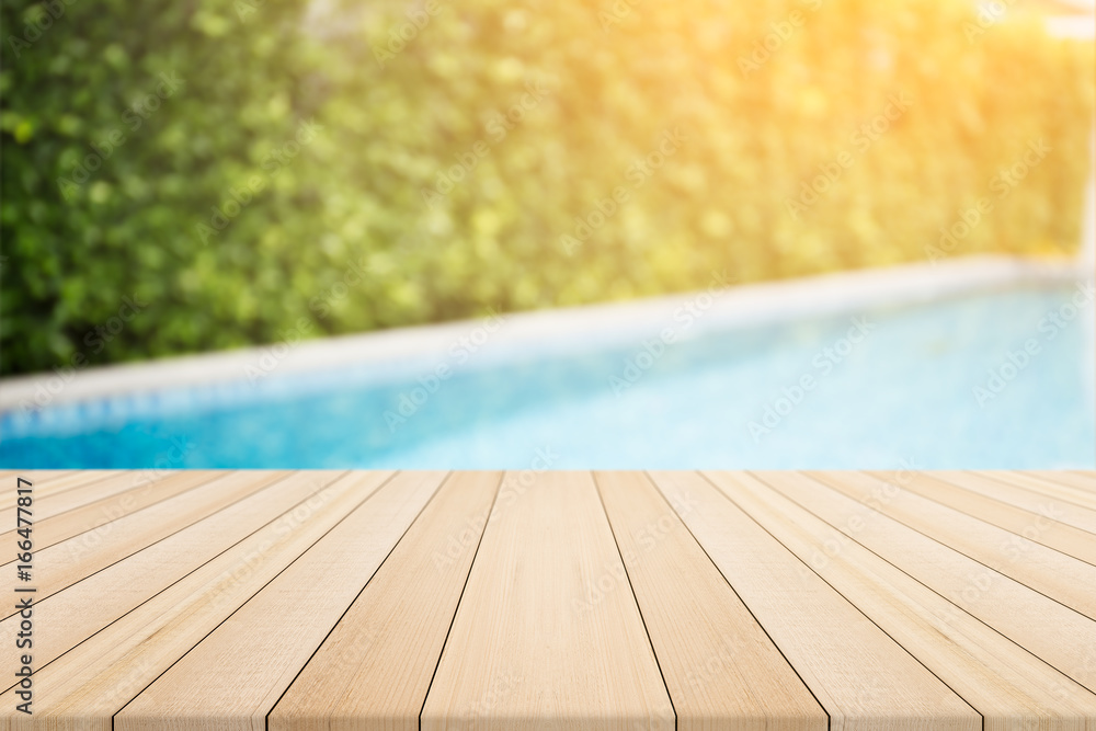 Empty wooden table in front with blurred background of swimming pool ...