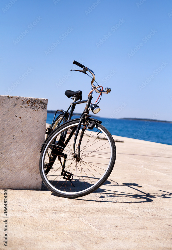 Bicycle on the fishing port of a small seaside town over blue sea and ...
