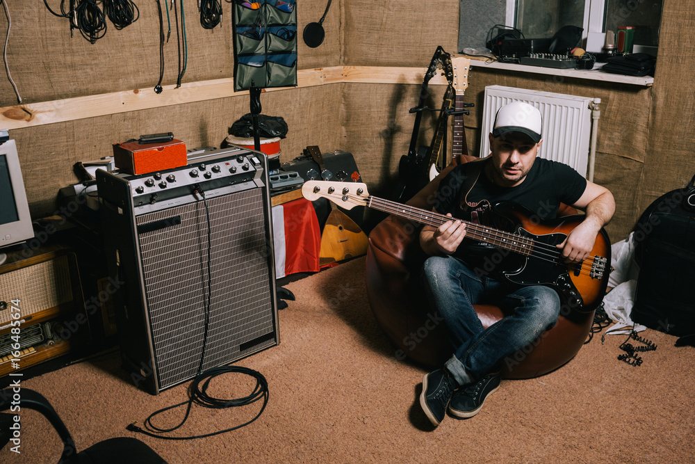 Guitarist in old garage music studio. Messy basement with instruments ...