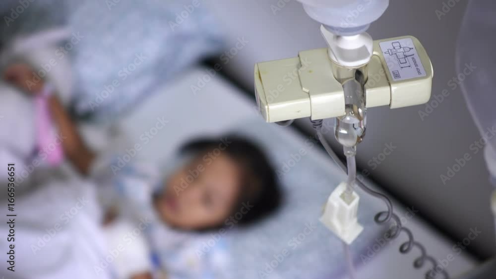 Close-up of intravenous saline drip with parent and sick little child ...