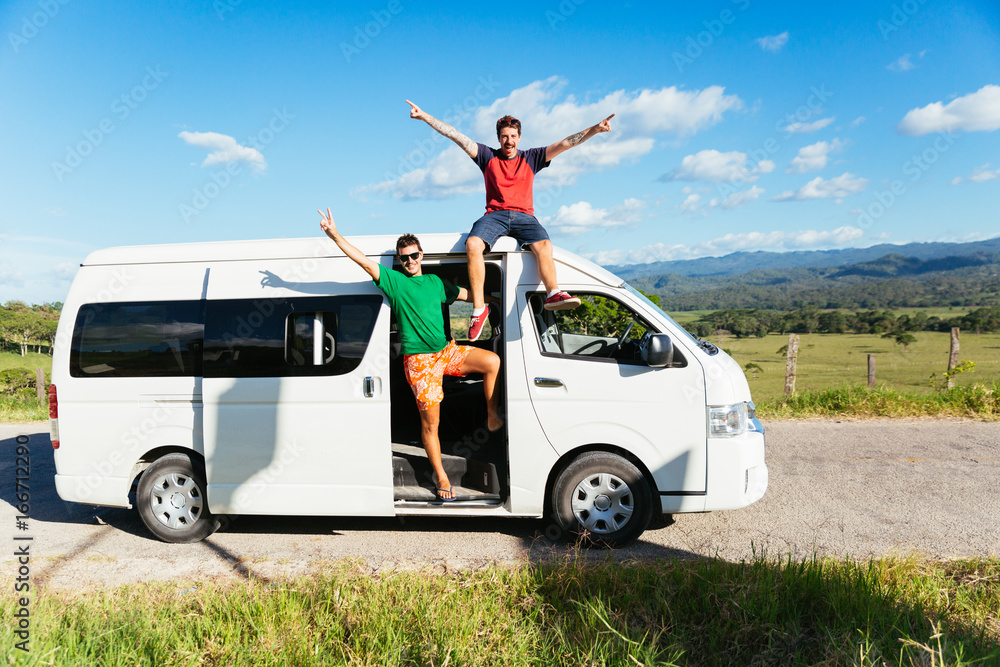 Two excited young men saluting from their white minivan during a break ...