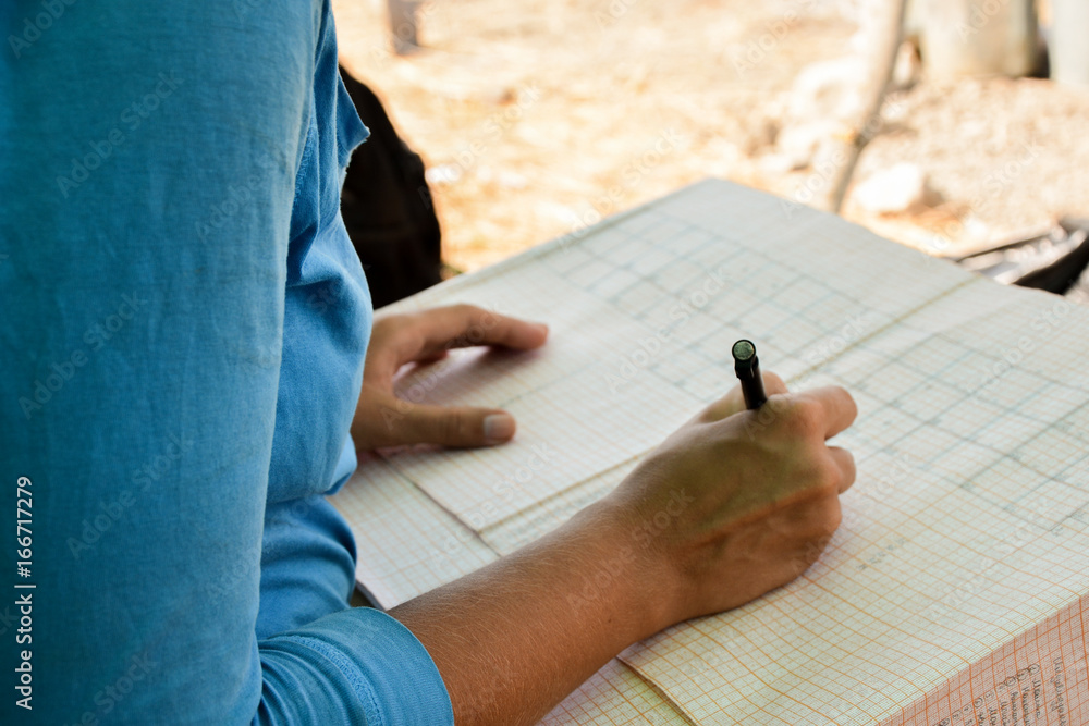 Man drawing on graph paper. A man's hand which draws pencil sketches of ...