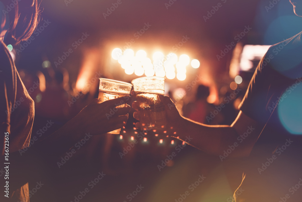 People with glasses toasting in front of silhouettes of concert crowd ...
