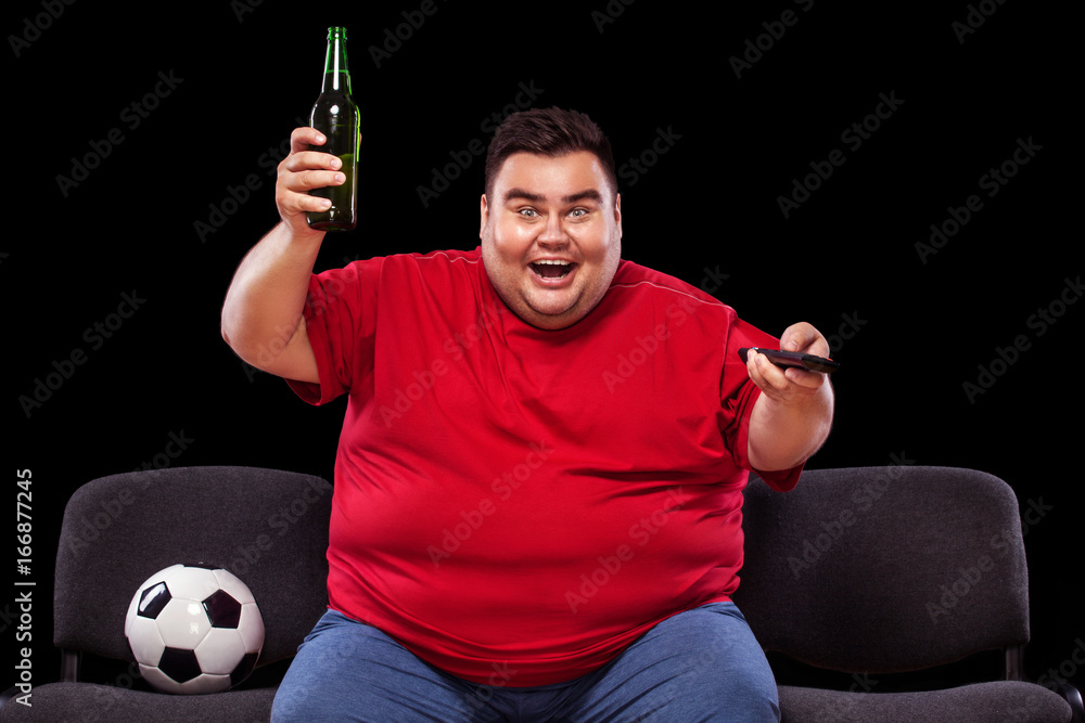 Soccer fun - happy and fat man watching tv, taking beer and soccer ball ...