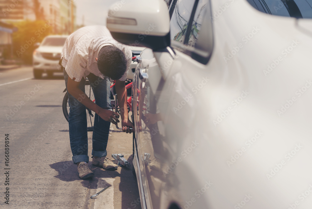 Young man changing flat tire on the road .Replacing the tires on the ...