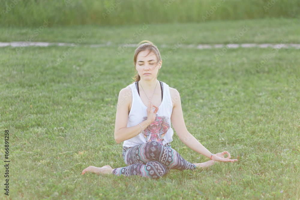 Yoga girl on nature background with green grass practicing nadi ...
