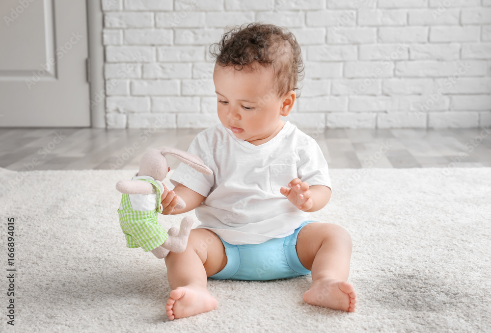 Cute baby girl sitting on carpet and playing with bunny near wet spot ...