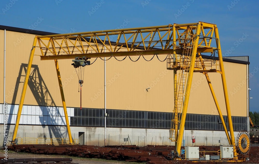 Gantry crane and its shadow on the factory wall. Raw materoals on the ...