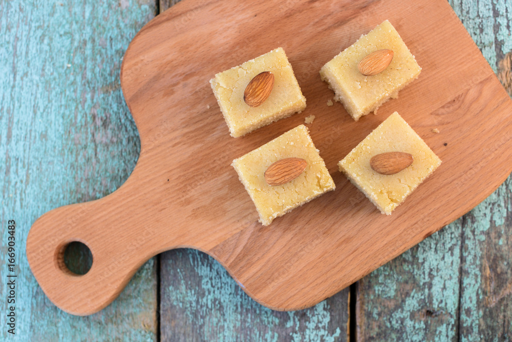 Homemade semolina halva with almonds cut in squares on wooden board top ...