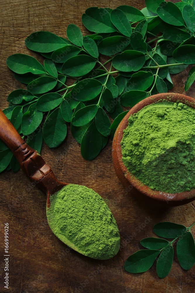 Overhead view of Moringa powder in an earthern pot on dark wooden ...