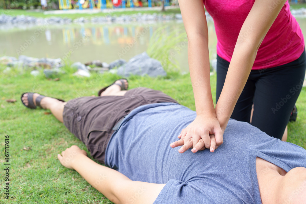 Woman giving cardiopulmonary resuscitation (CPR) to a man at public ...