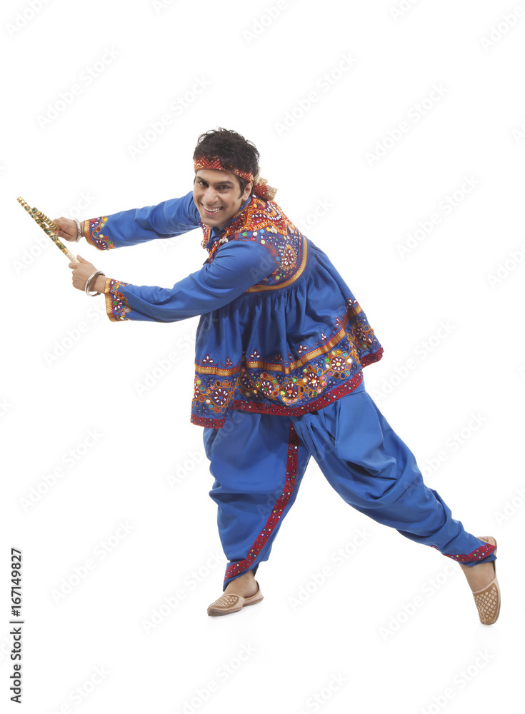 Portrait of an Indian man performing Dandiya Raas over white background ...