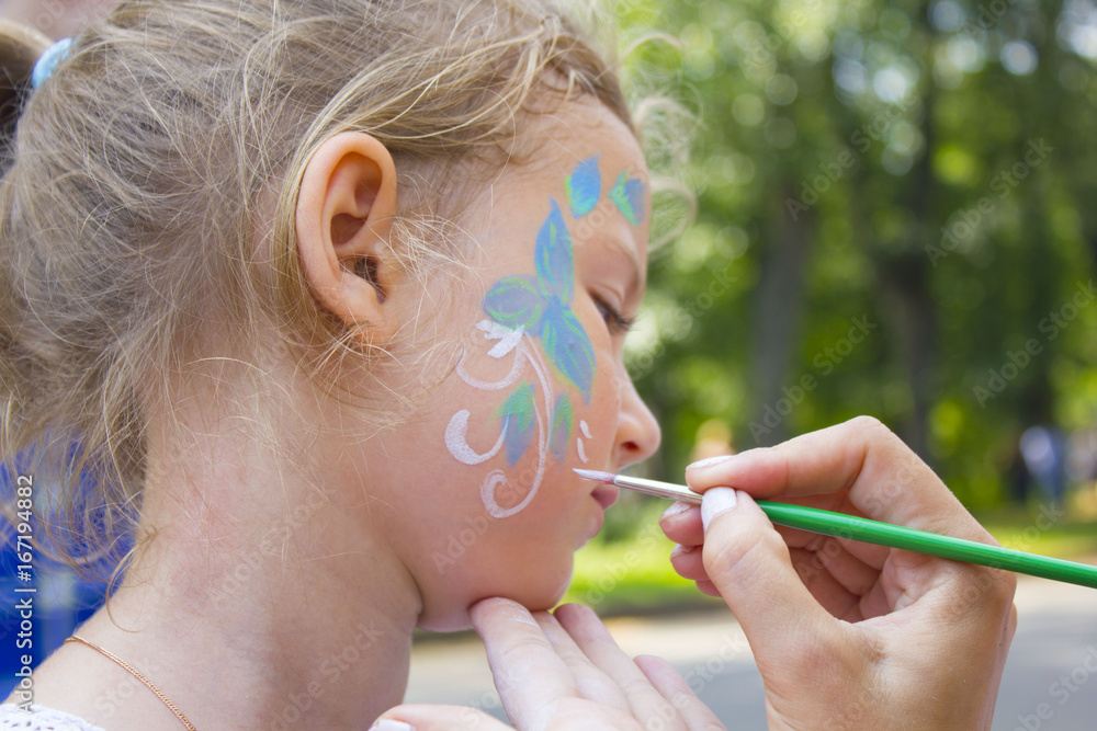 little girl getting her face painted like a butterfly by face painting ...