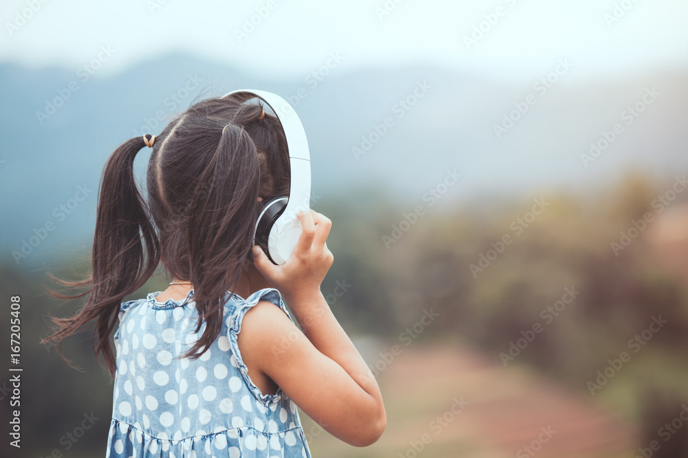 Back view of cute asian child girl having fun to listen the music in ...