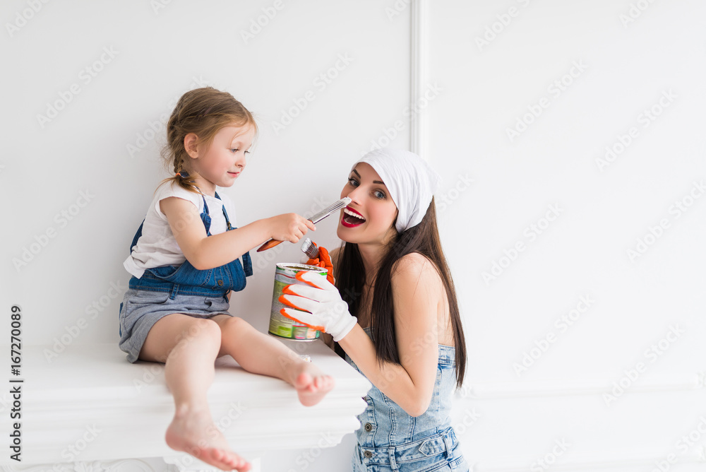 The young happy mother with her daughter do repair at home, they keep ...