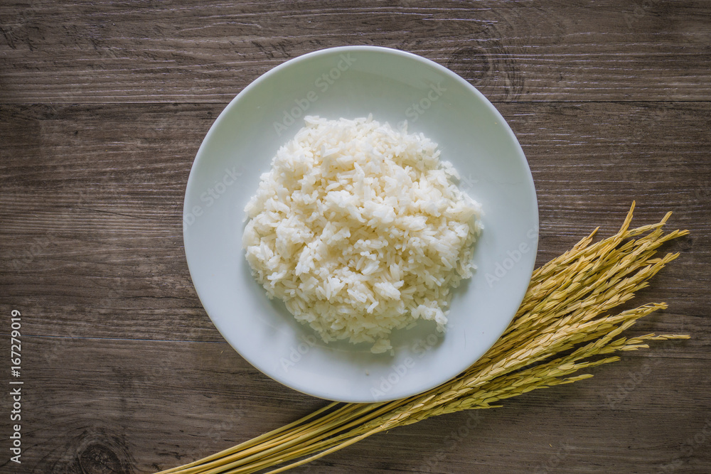 Top view rice in white plate on gray wooden background and dried paddy ...