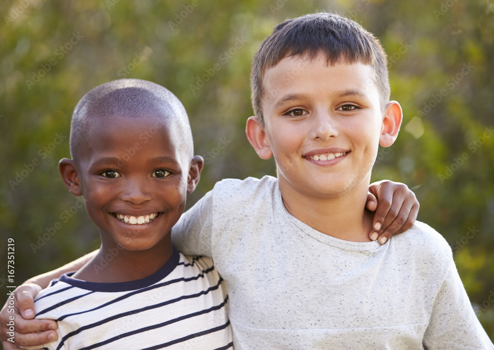 Two boys, arms around each other smiling to camera outdoors Stock Photo ...