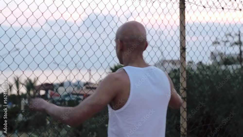Angry bald man doing blows on fence grid. Angry bald man. Moor street ...