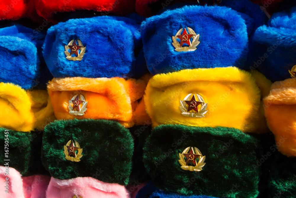 Rows of russian winter hats of different colors with army emblems at ...