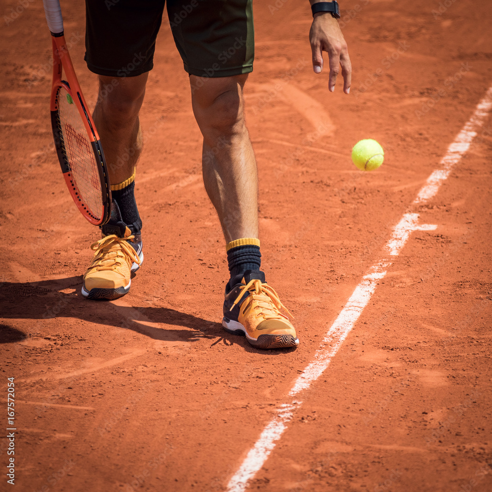 Tennis player with a ball and a rackey on a clay court at Rolland ...