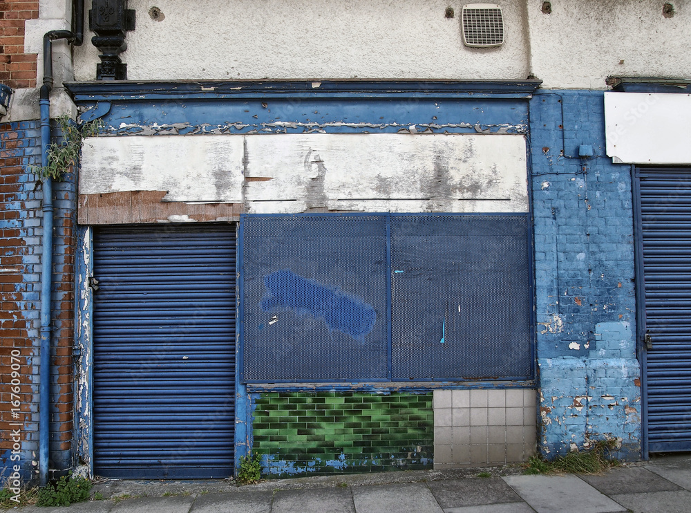 Abandoned Derelict Shop With Storefront Boarded Up With Peeling Blue ...