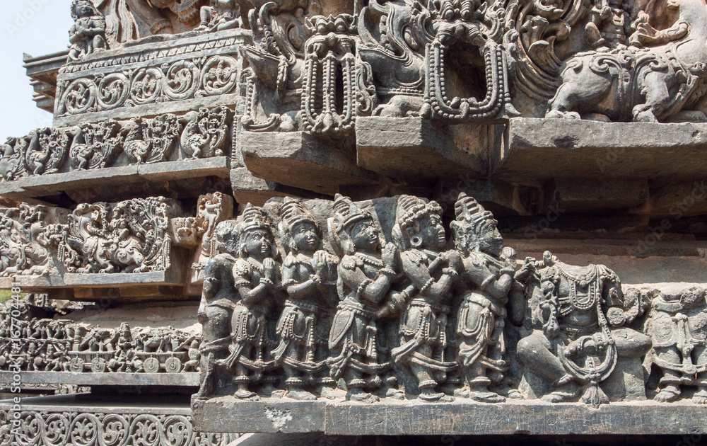 Ancient praying people on old wall of Hindu temple. Sculpured stone ...