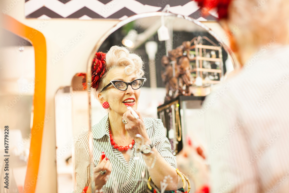 Mirror image of quirky vintage woman applying lipstick in antique and ...