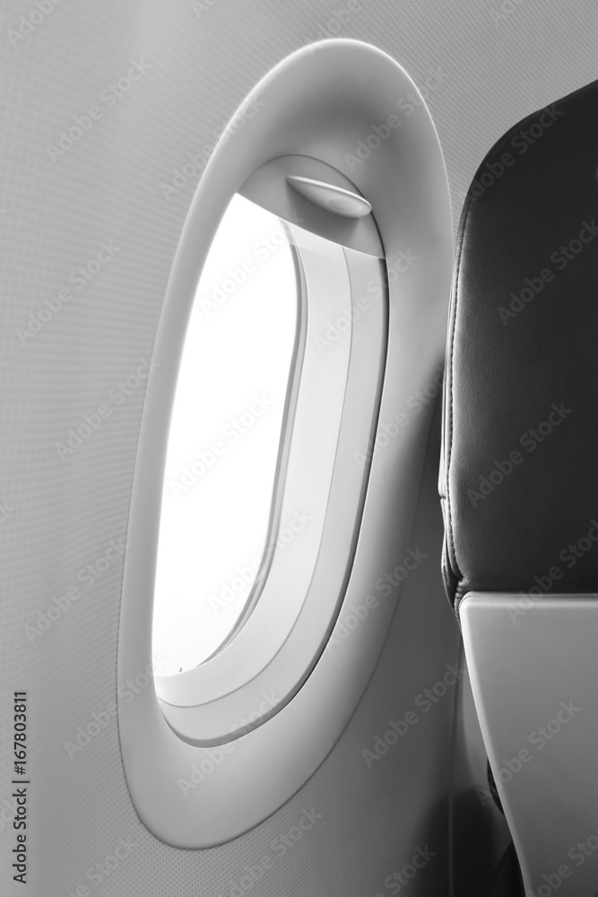 Gray aircraft window and backside of the passenger seat with black ...