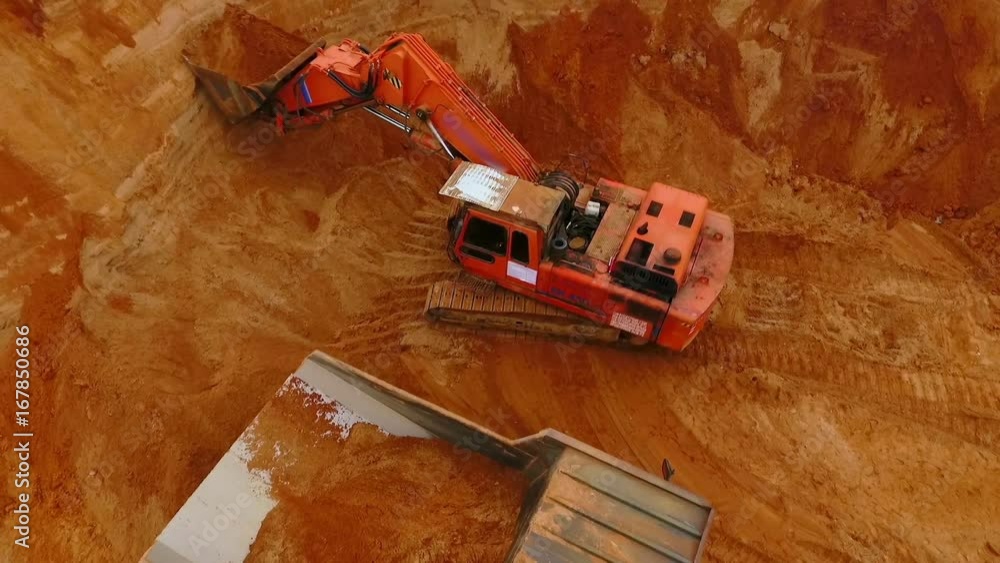 View from above of mining excavator pouring sand in dumper truck ...