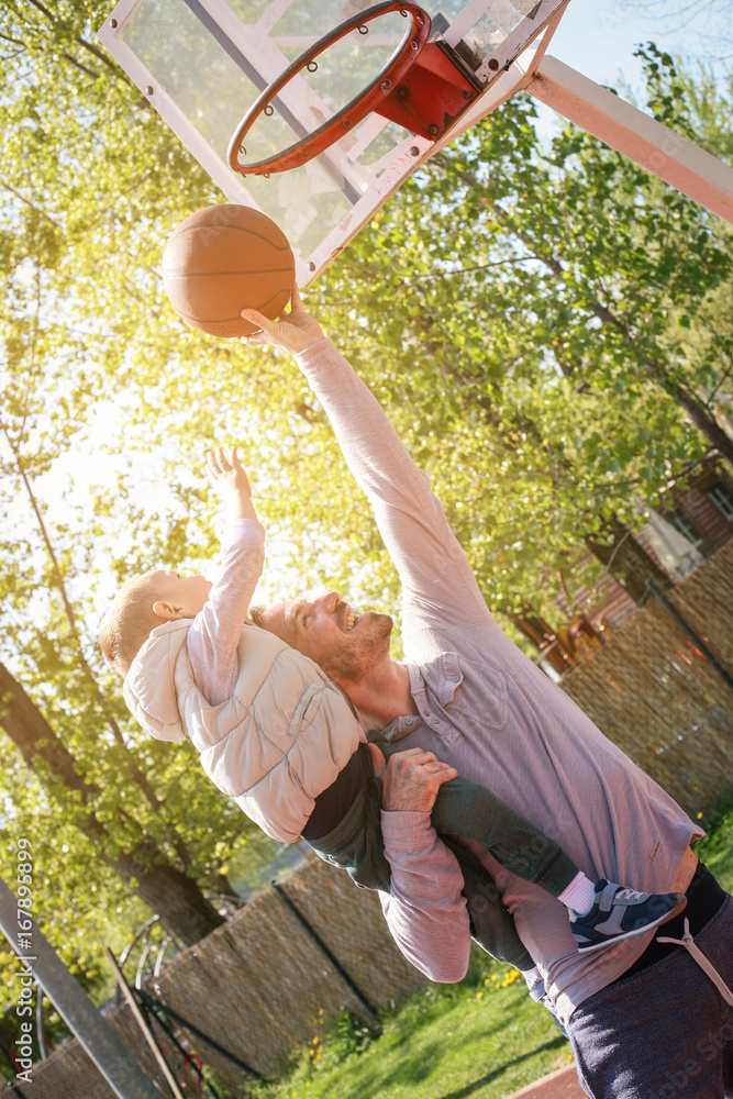 Dad and his son playing basketball together. Enjoying in spring day ...