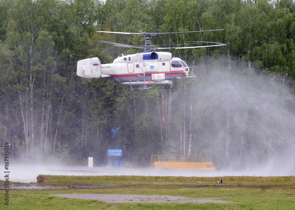 Fire-fighting helicopter КА-32 А recovers water from the reservoir at ...