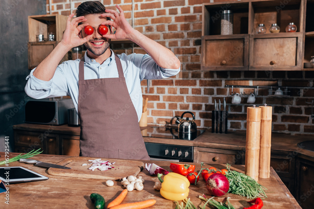 funny young man covering eyes with tomatoes while cooking Stock Photo ...