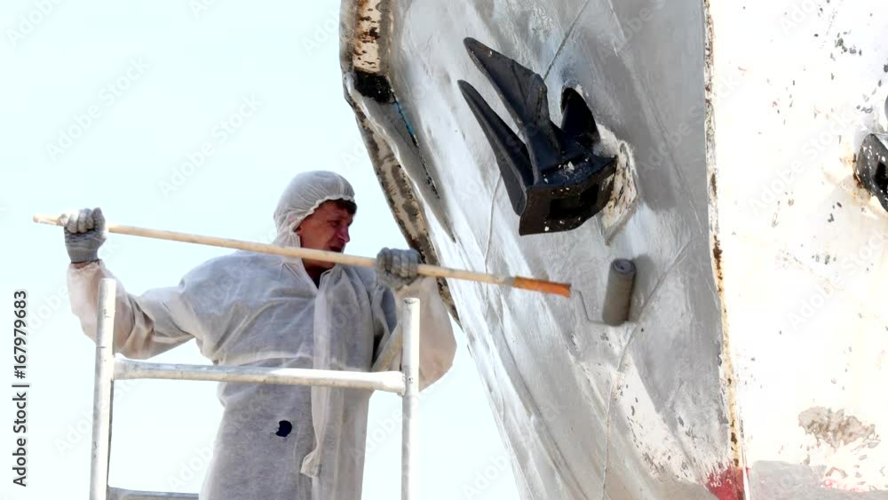 Worker paints metal of old rusty ship at shipyard in port of Moscow ...