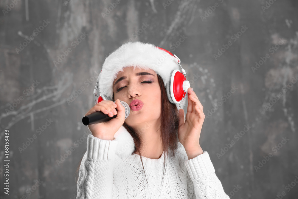 Beautiful young woman in Santa hat singing Christmas songs on grunge ...