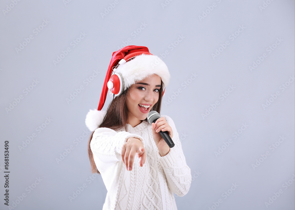 Beautiful young woman in Santa hat singing Christmas songs on light ...