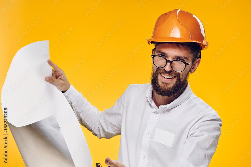 Engineer with a beard in a helmet on a yellow background holds a ...