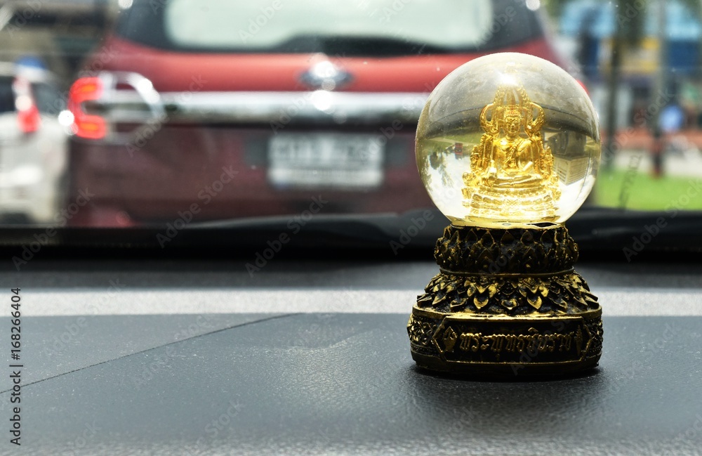 little buddha statue behind windshield in car ,text in thai language is ...
