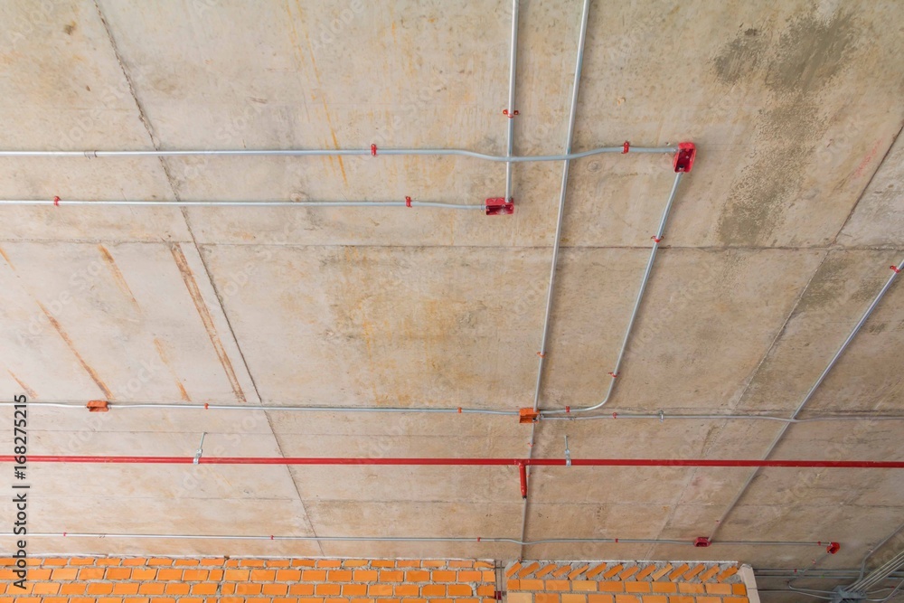 Metal pipes in Construction and fire sprinkler on red pipe are hanging ...
