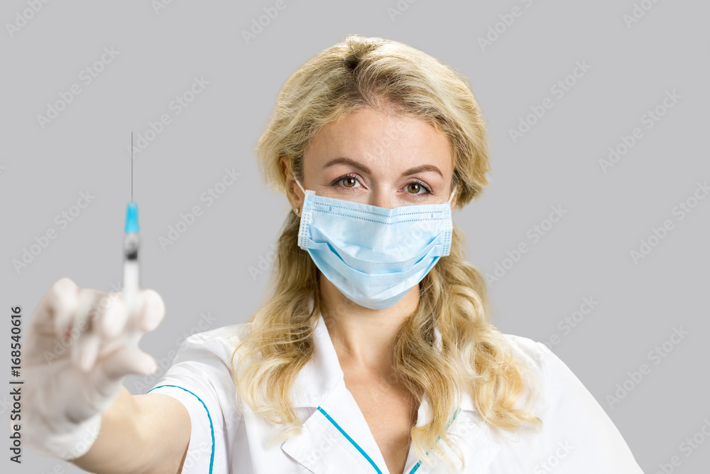 Young female doctor or nurse in surgical mask holding an injection in ...