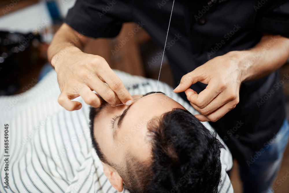 Crop barber threading eyebrows of client Stock Photo | Adobe Stock